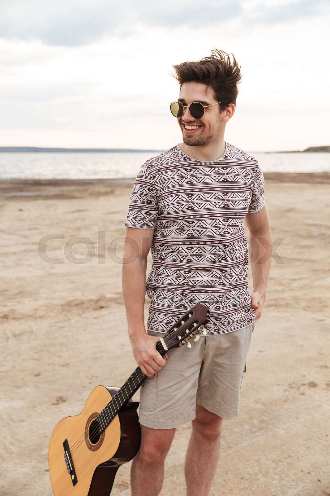 Cheerful young man carrying guitar | Stock image | Colourbox