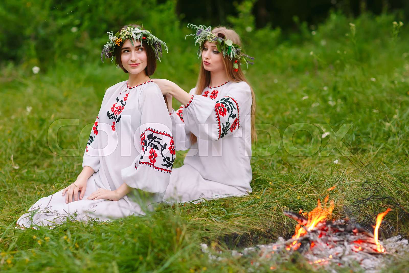 Midsummer. Two girls in the Slavic clothes weave braids in the hair ...