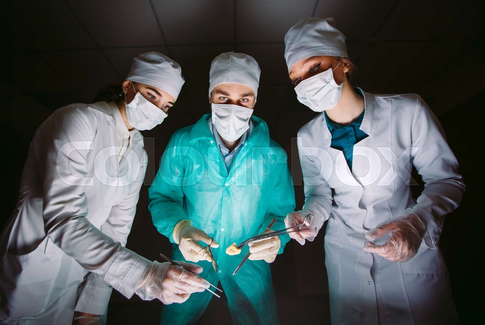 The surgeon makes an operation in a dark room. | Stock image | Colourbox