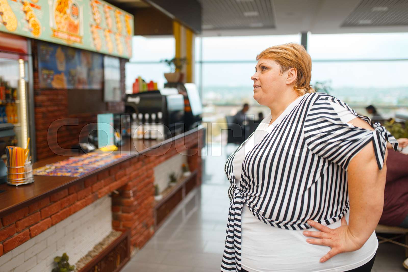 Fat woman at the fast food restaurant menu | Stock image | Colourbox