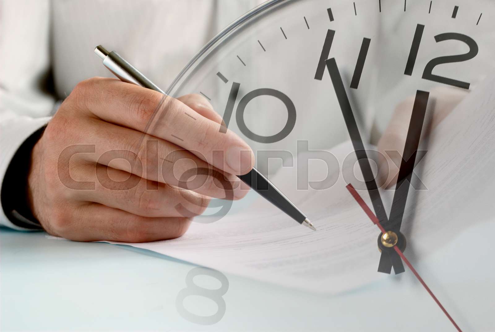 Man writing on papers and clock | Stock image | Colourbox