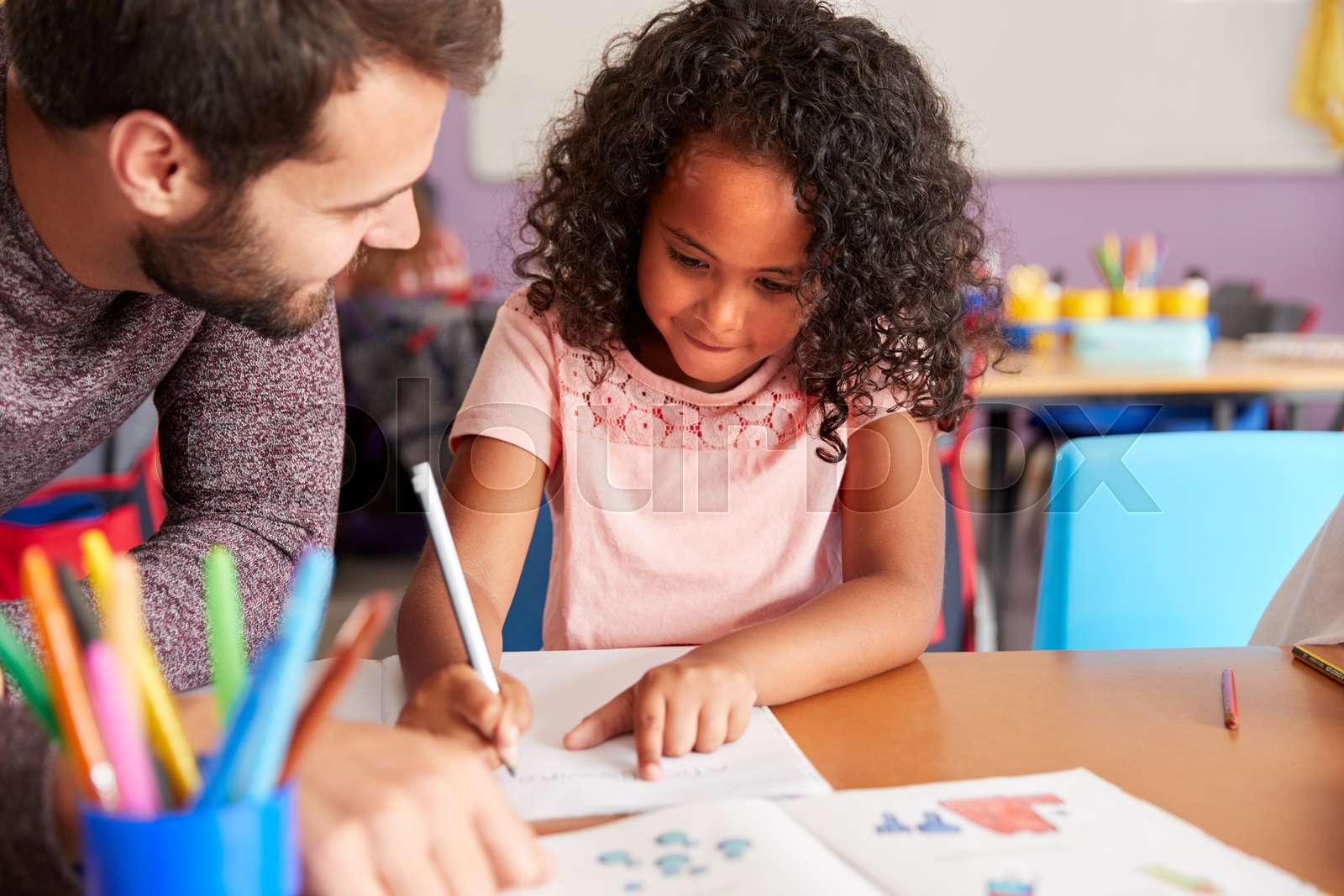 Elementary School Teacher Giving Female Pupil One To One Support In ...