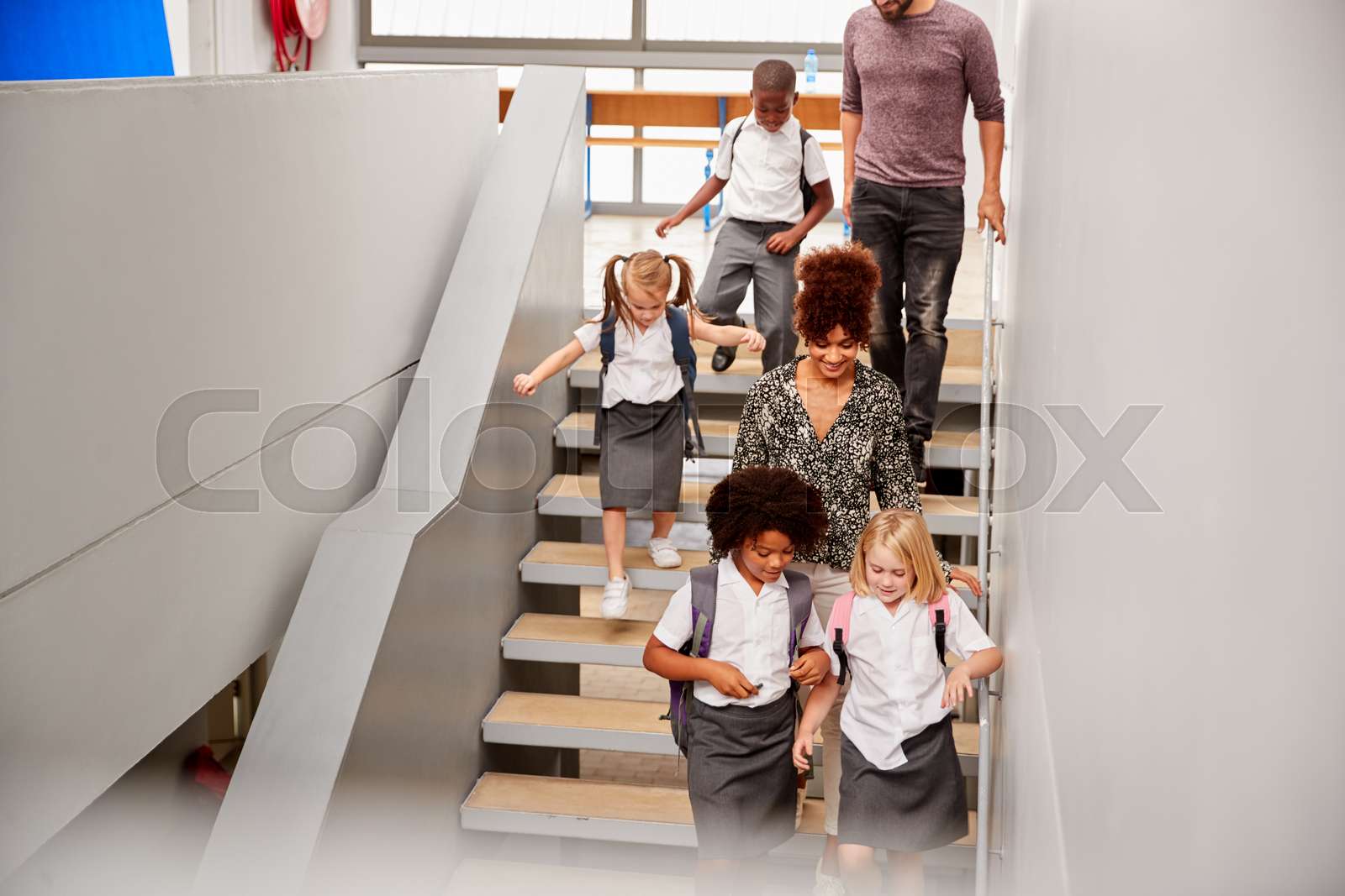 Teacher And Pupils Walking Down Stairs In Busy Elementary School ...