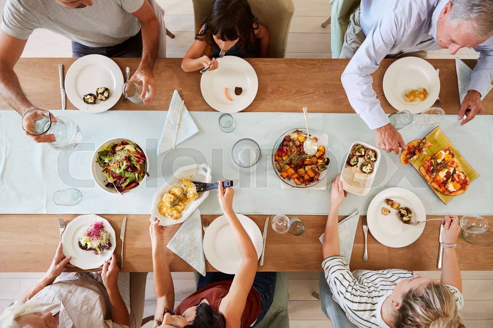 Three generation white family sitting at a dinner table together ...