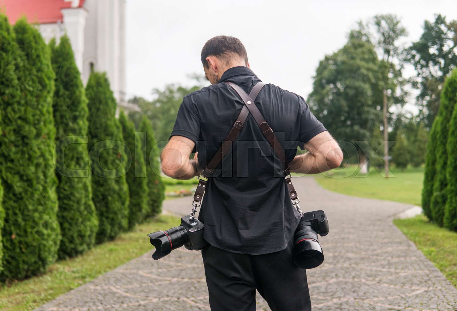 Back of professional wedding photographer in black shirt and with a two ...