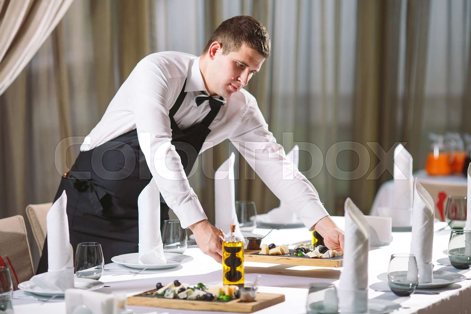 Waiter serving table in the restaurant preparing to receive guests ...