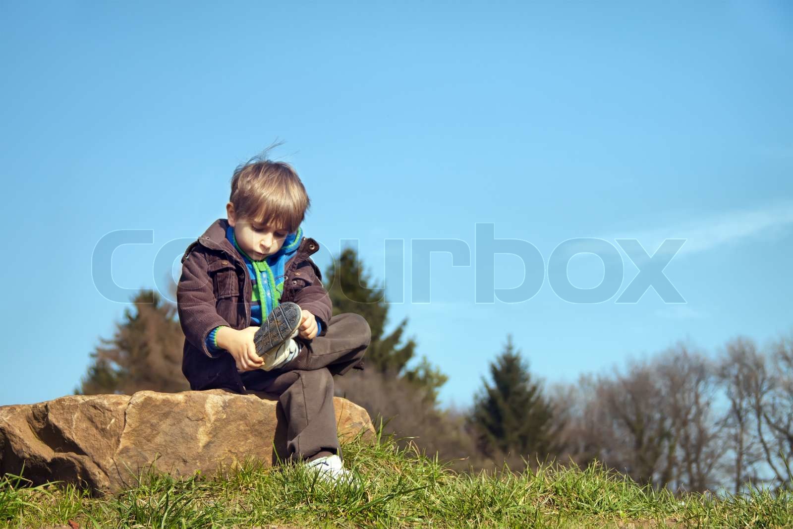 A little boy sitting on a rock. | Stock image | Colourbox