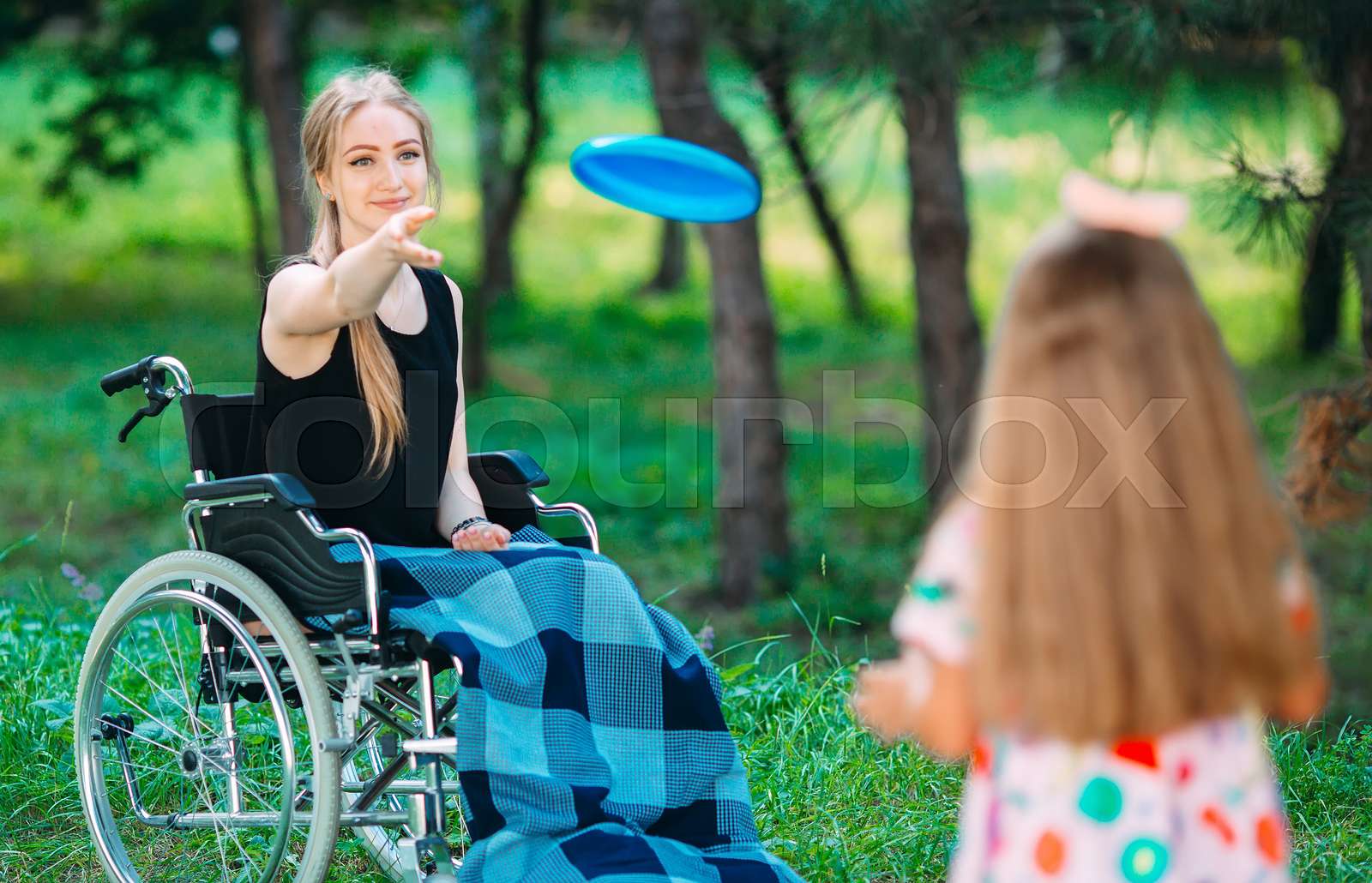 A young disabled girl plays Frisbee with her younger sister ...