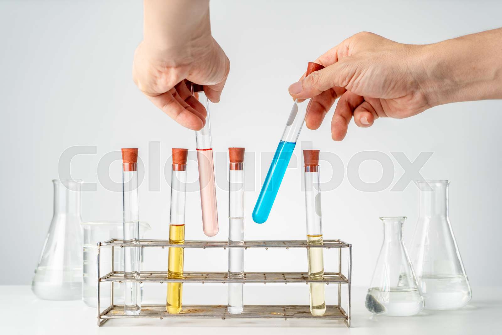 Male's hands holding chemistry lab's test tubes, putting them back in ...