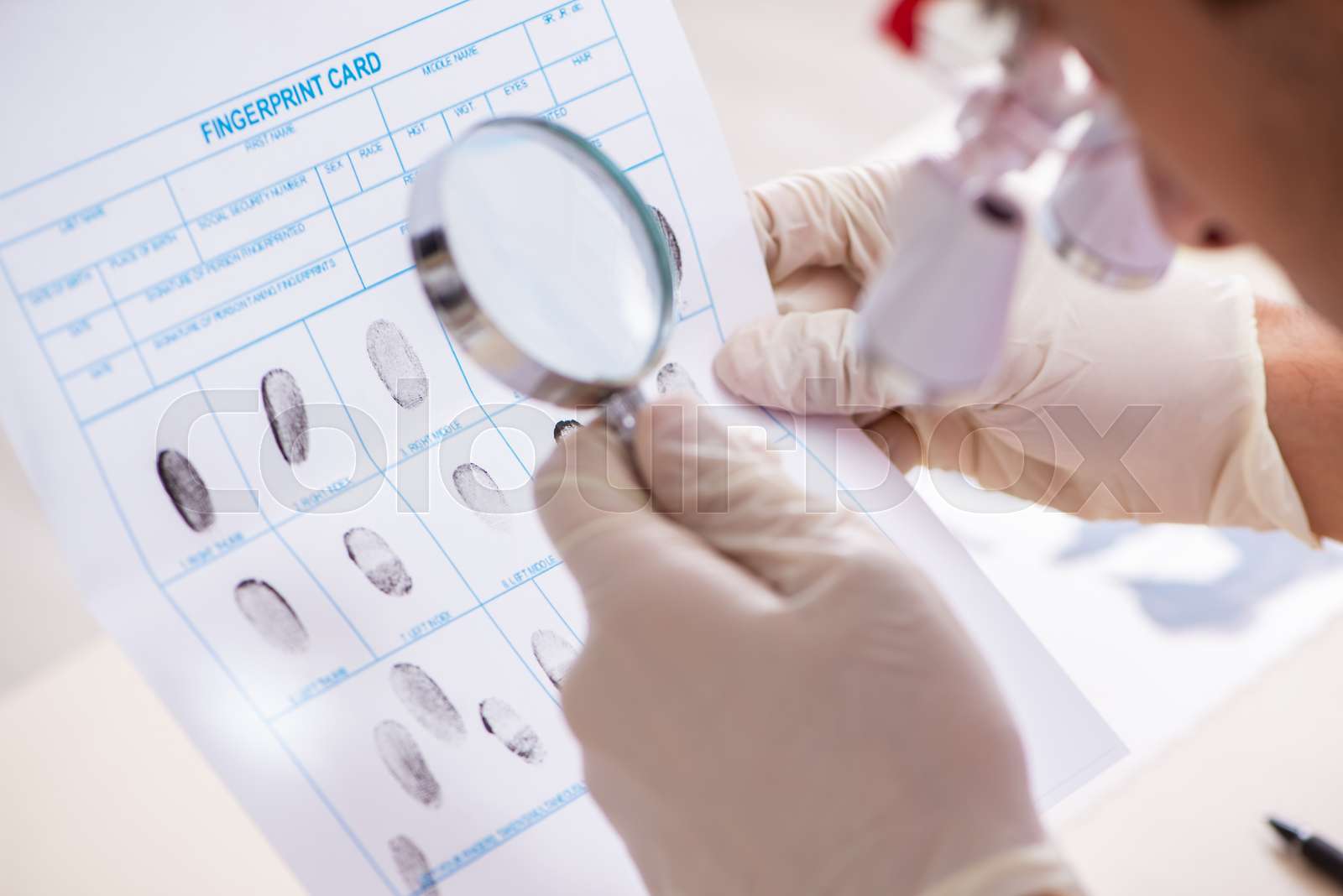 Forensic expert studying fingerprints in the lab | Stock image | Colourbox
