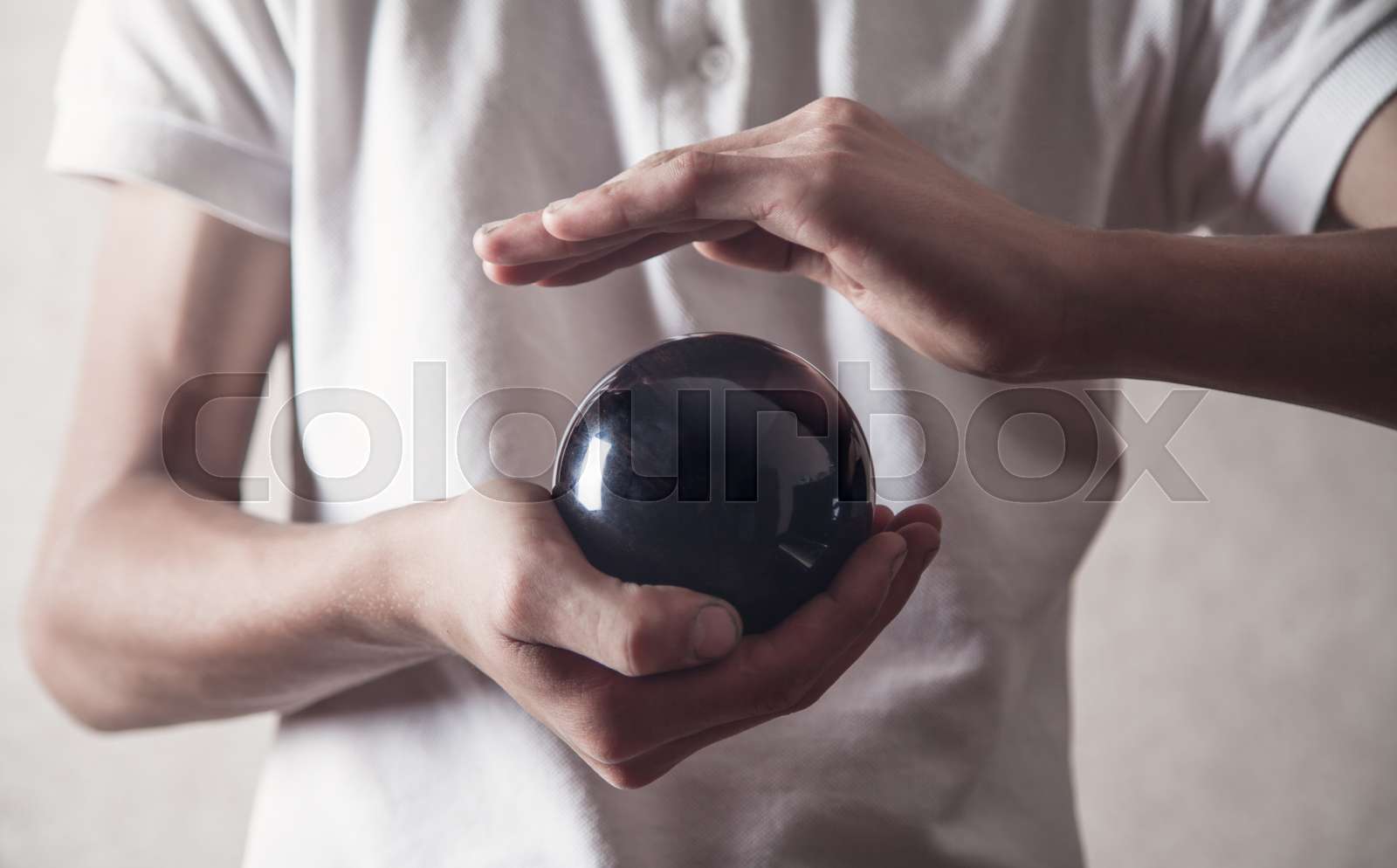 Man holding black crystal ball. | Stock image | Colourbox
