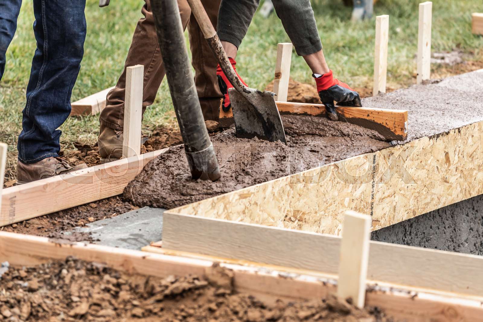 Construction Workers Pouring And Leveling Wet Cement Into Wood Framing ...
