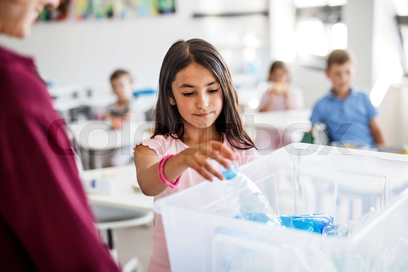 A teacher with small school kids in classroom learning about waste ...