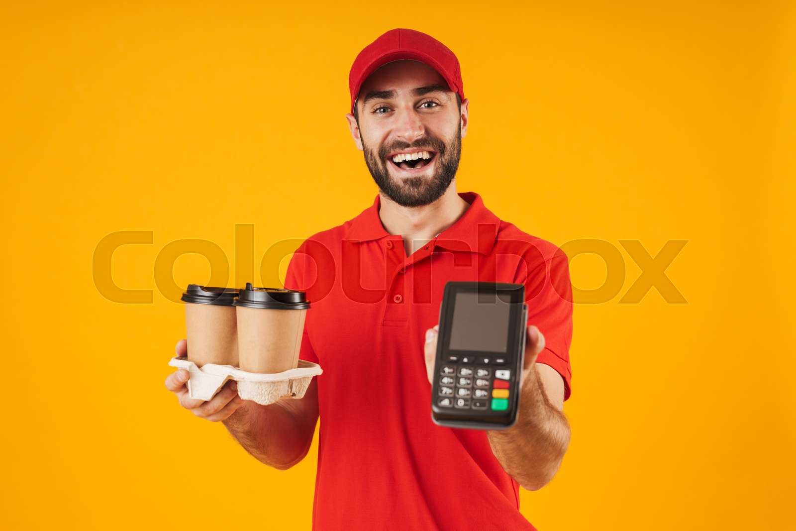 Portrait of young delivery man in red uniform holding takeaway coffee ...