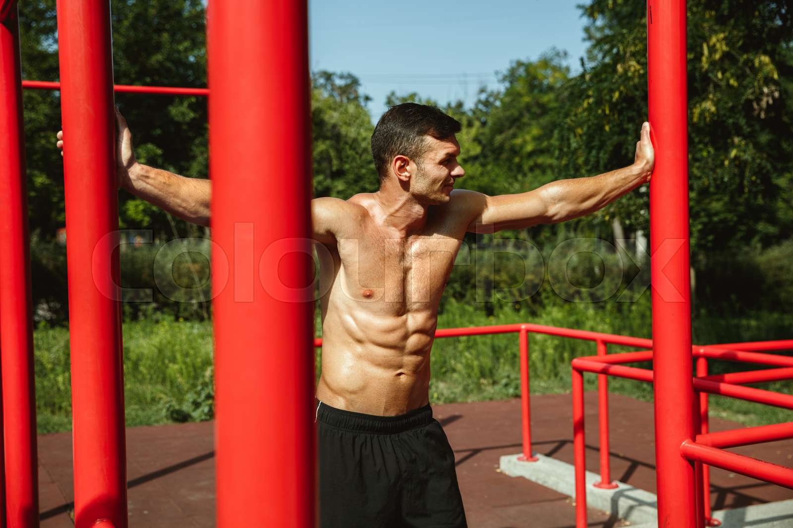 Young muscular man while doing his workout outside at playground ...
