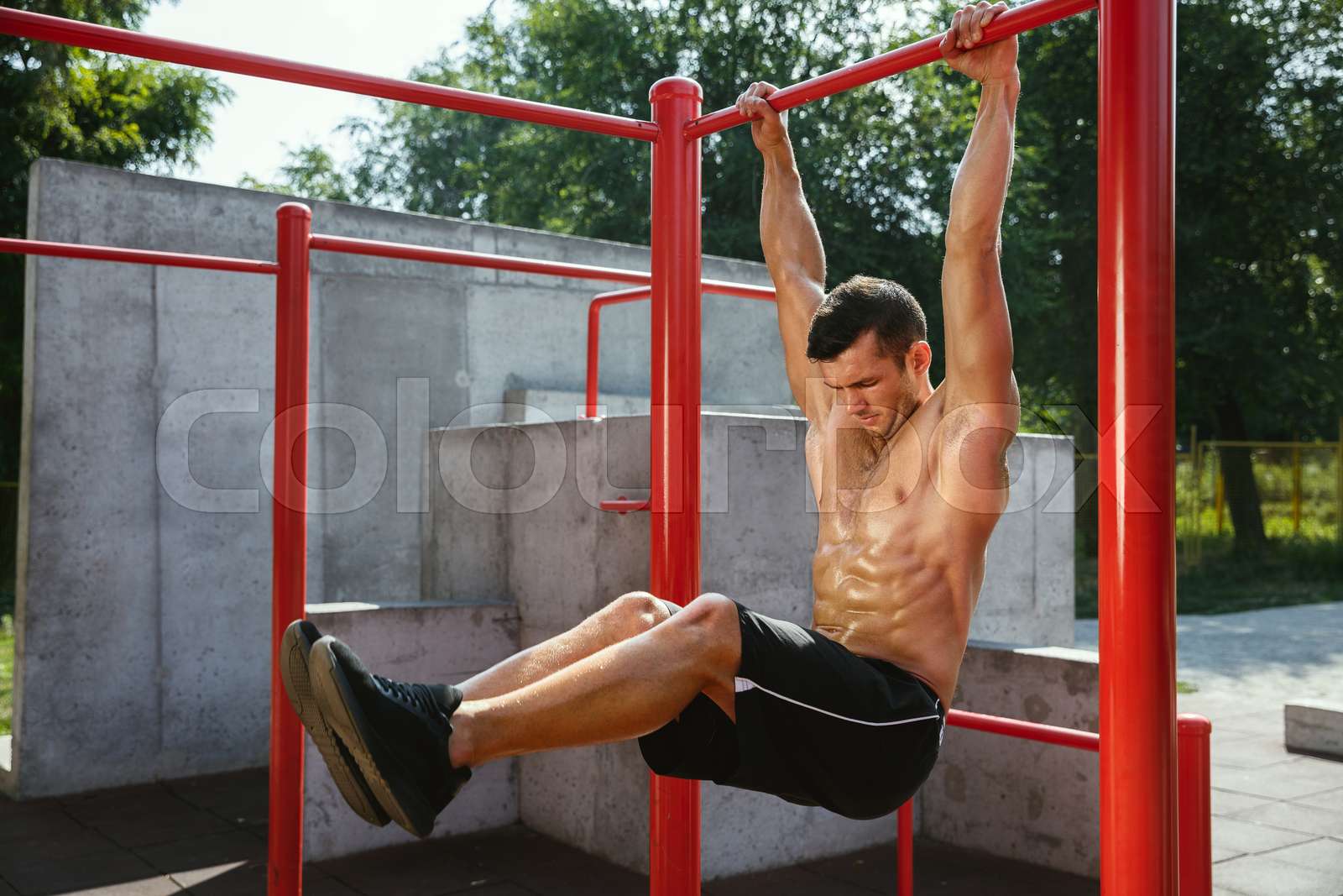 Young muscular man while doing his workout outside at playground ...