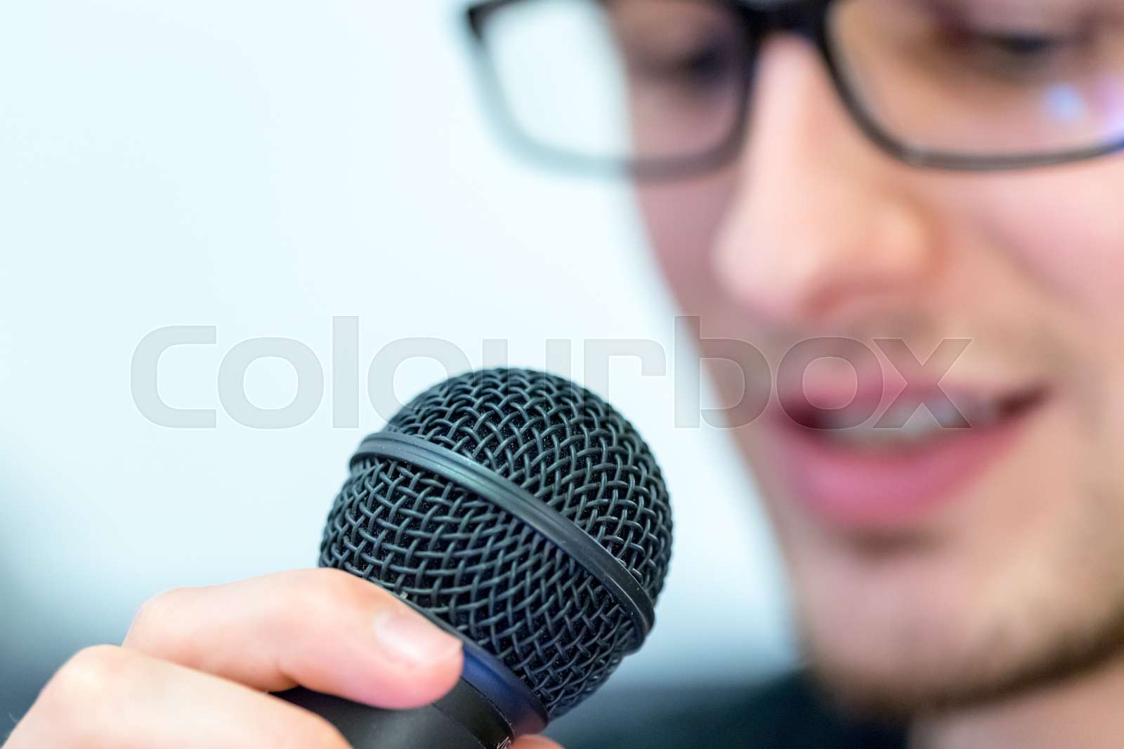 Speaking in the microphone: Young man with blurry face is taking into ...