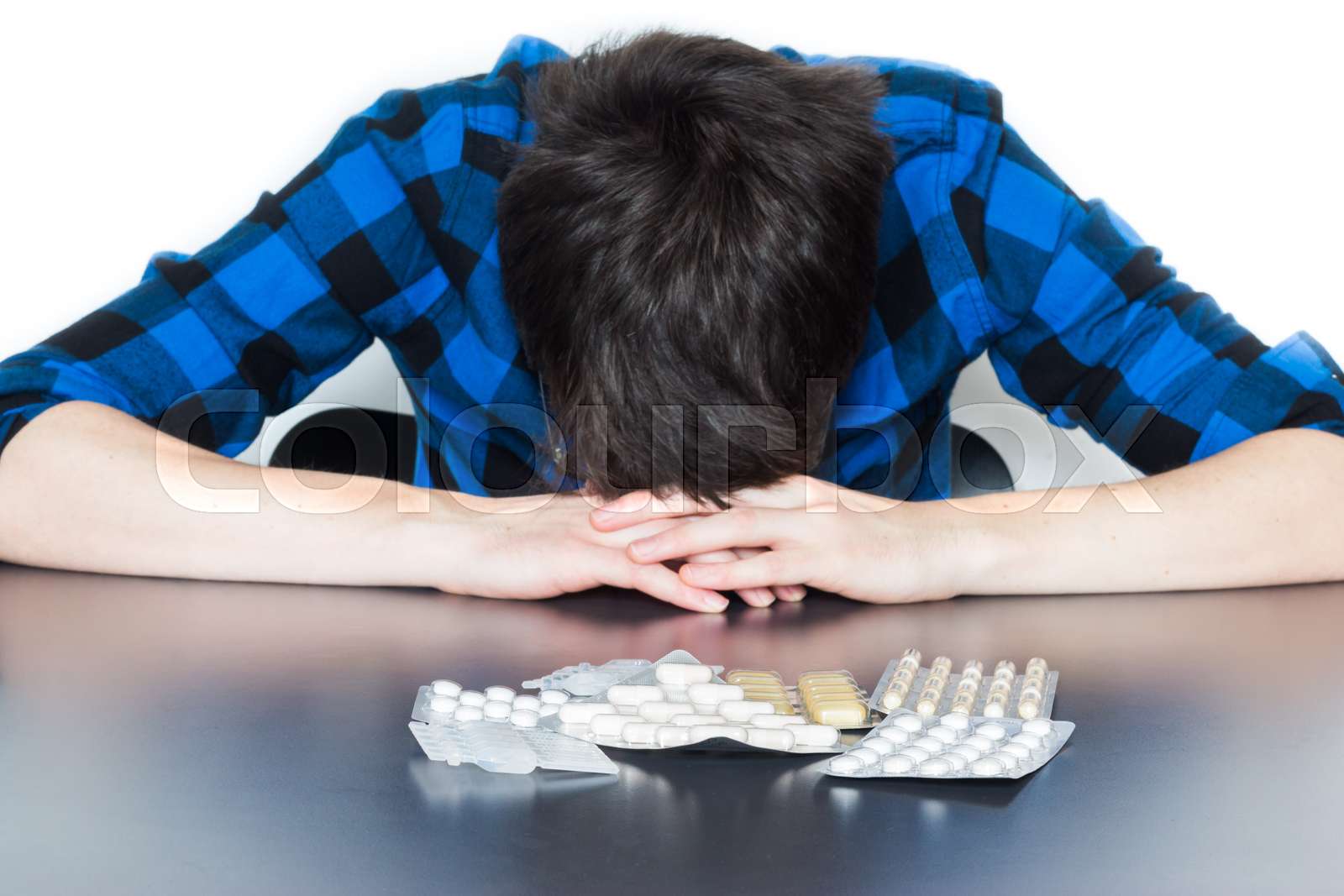 Depressed man taking drugs. Young man sitting on a table, drugs and ...
