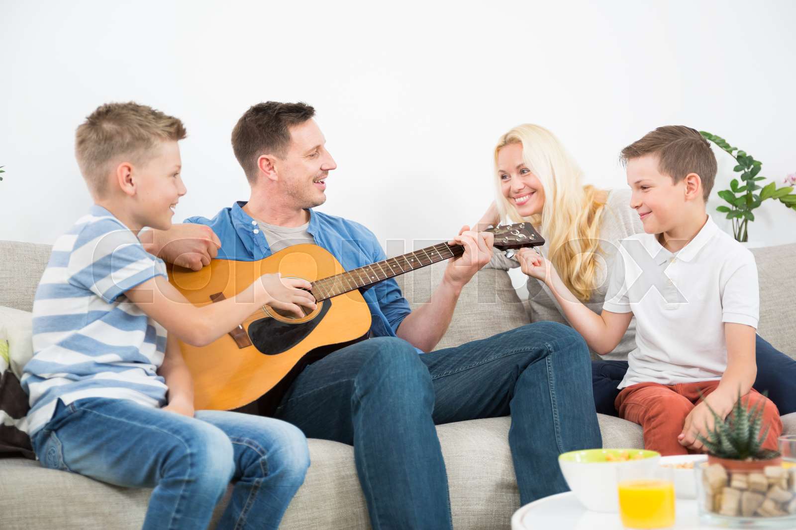 Happy caucasian family smiling, playing guitar and singing songs ...