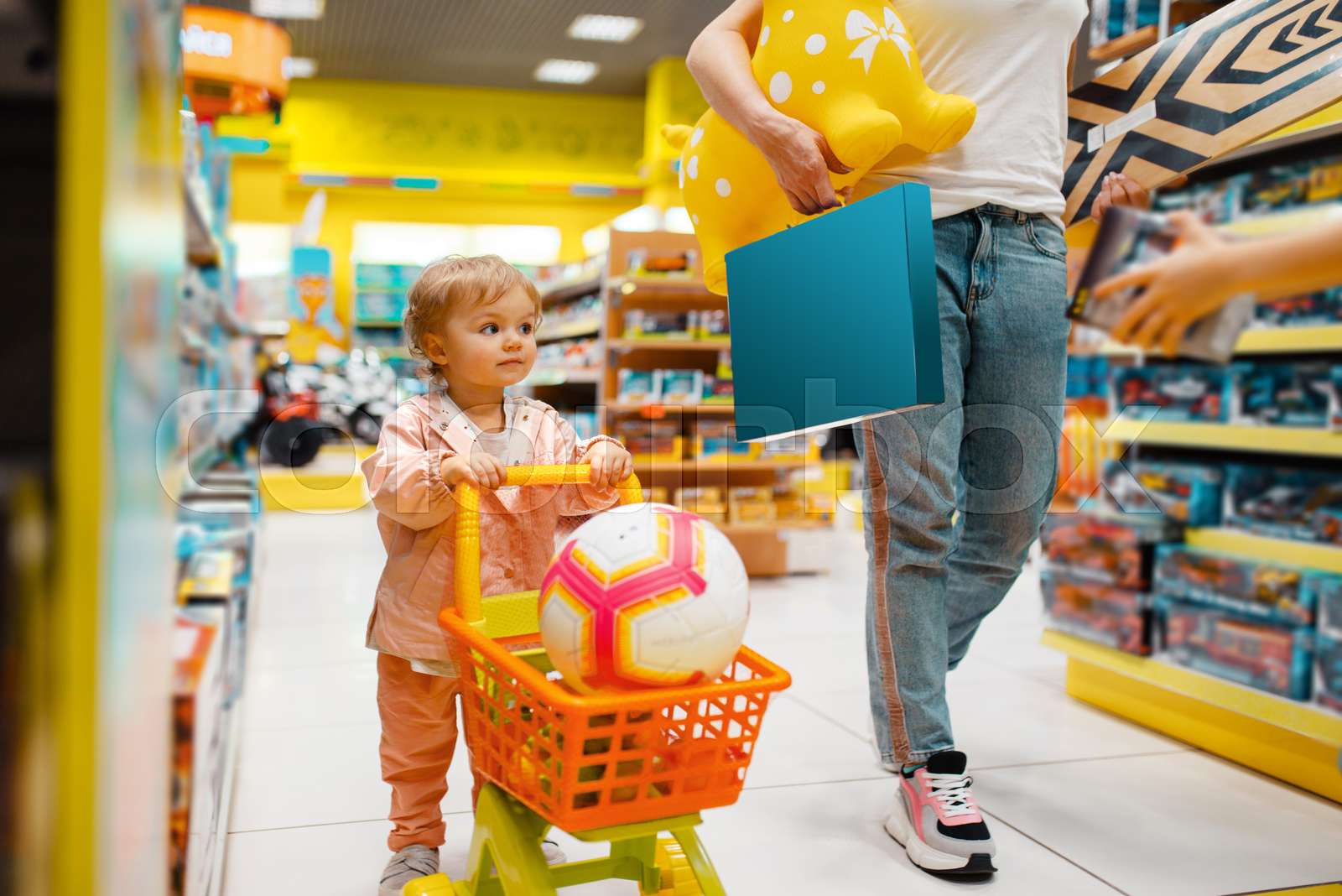 Mother with girl buying a lot of toys in store | Stock image | Colourbox