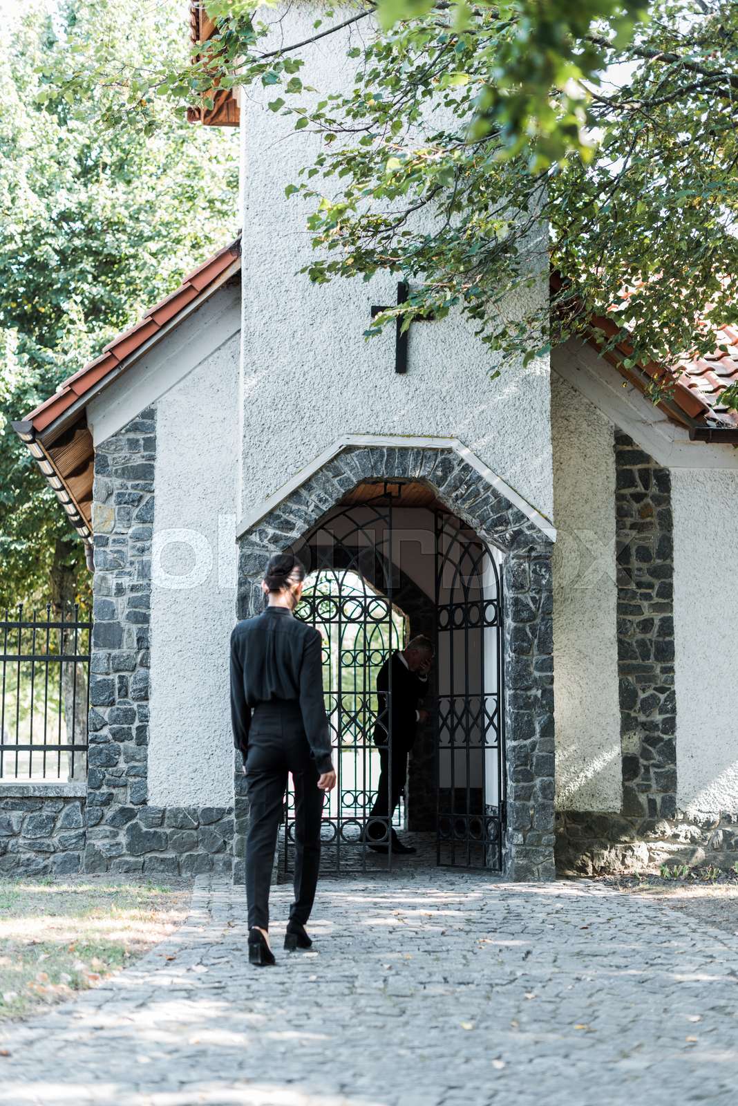 back view of woman walking into church near trees | Stock image | Colourbox