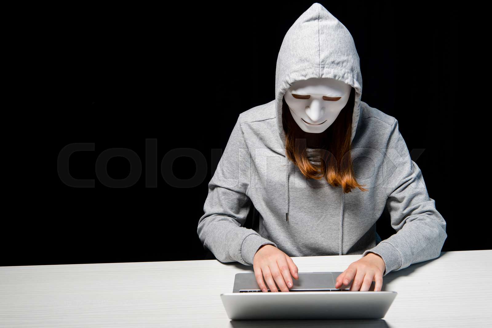 Anonymous Internet Troll In Mask Typing On Laptop Keyboard Isolated On Black Stock Image
