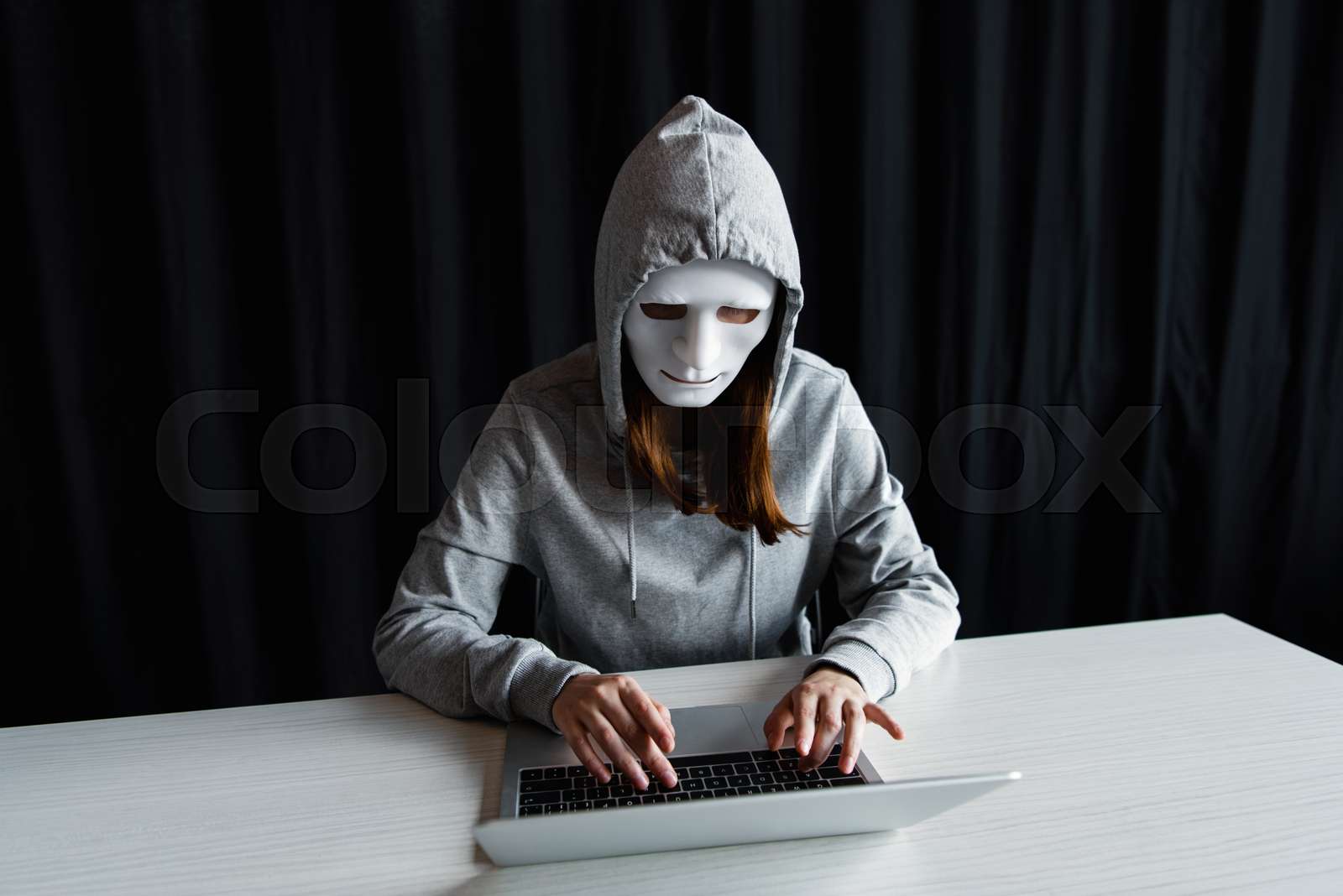 anonymous internet troll in mask typing on laptop keyboard on black ...