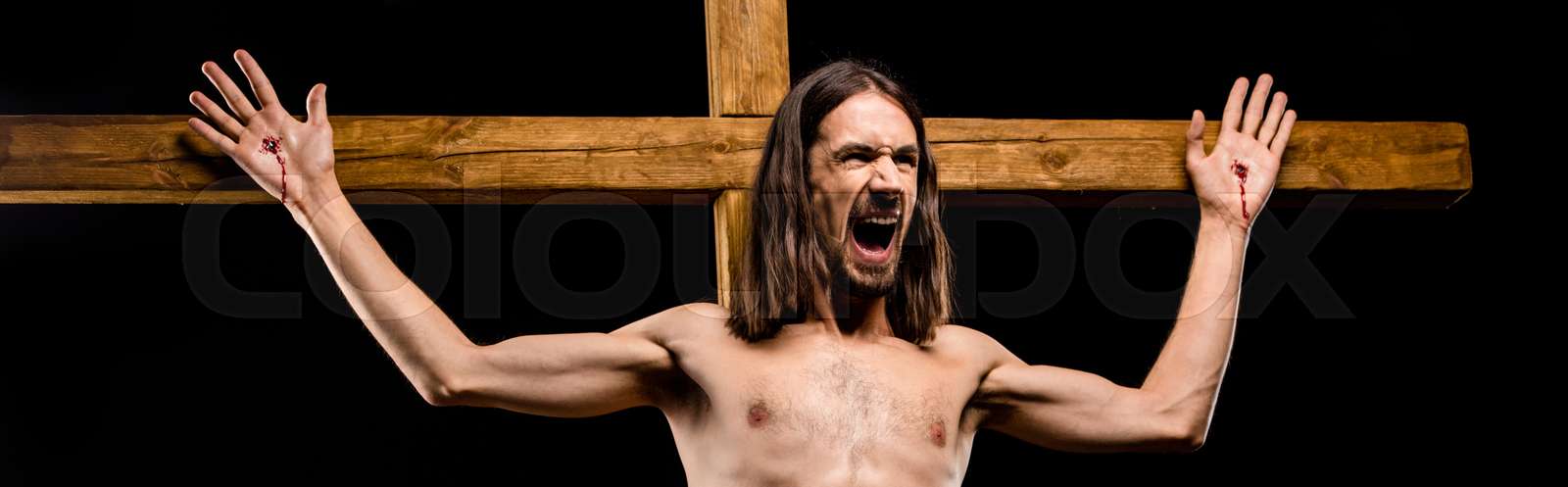 panoramic shot of shirtless man crucified on wooden cross screaming ...