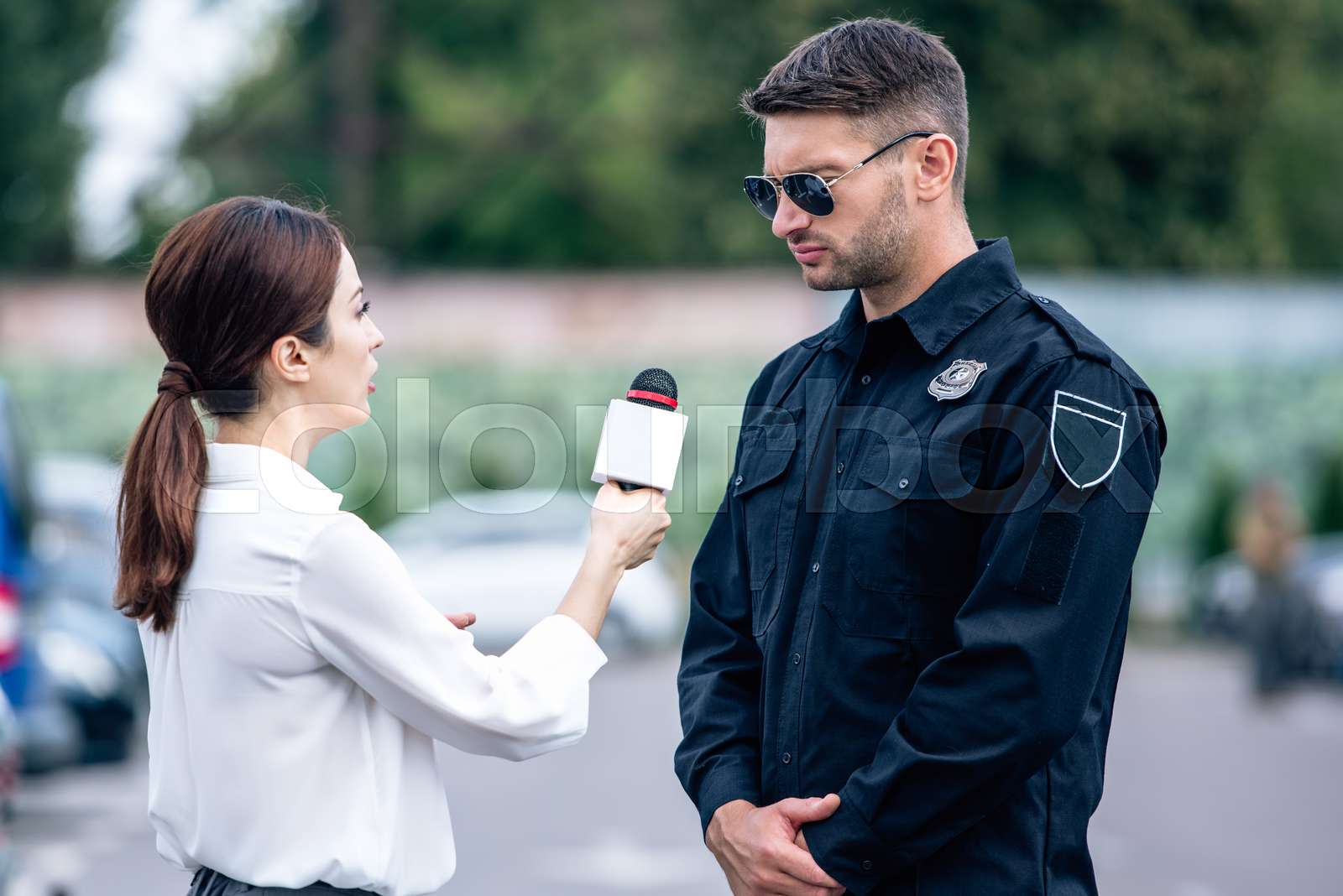 journalist holding microphone and talking with handsome policeman in ...