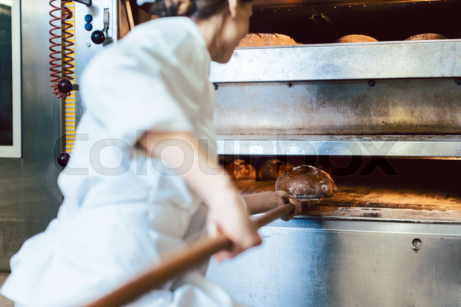 Baker putting bread in the bakery oven | Stock image | Colourbox