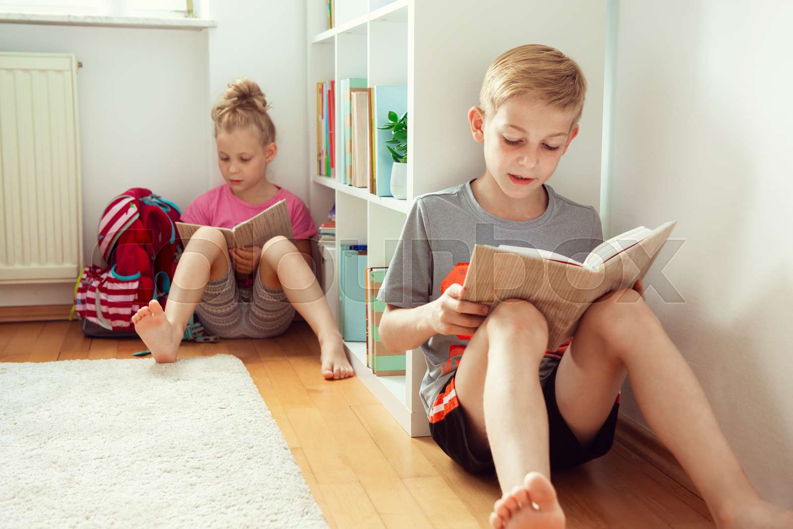Happy children reading books on the floor at the school library | Stock ...