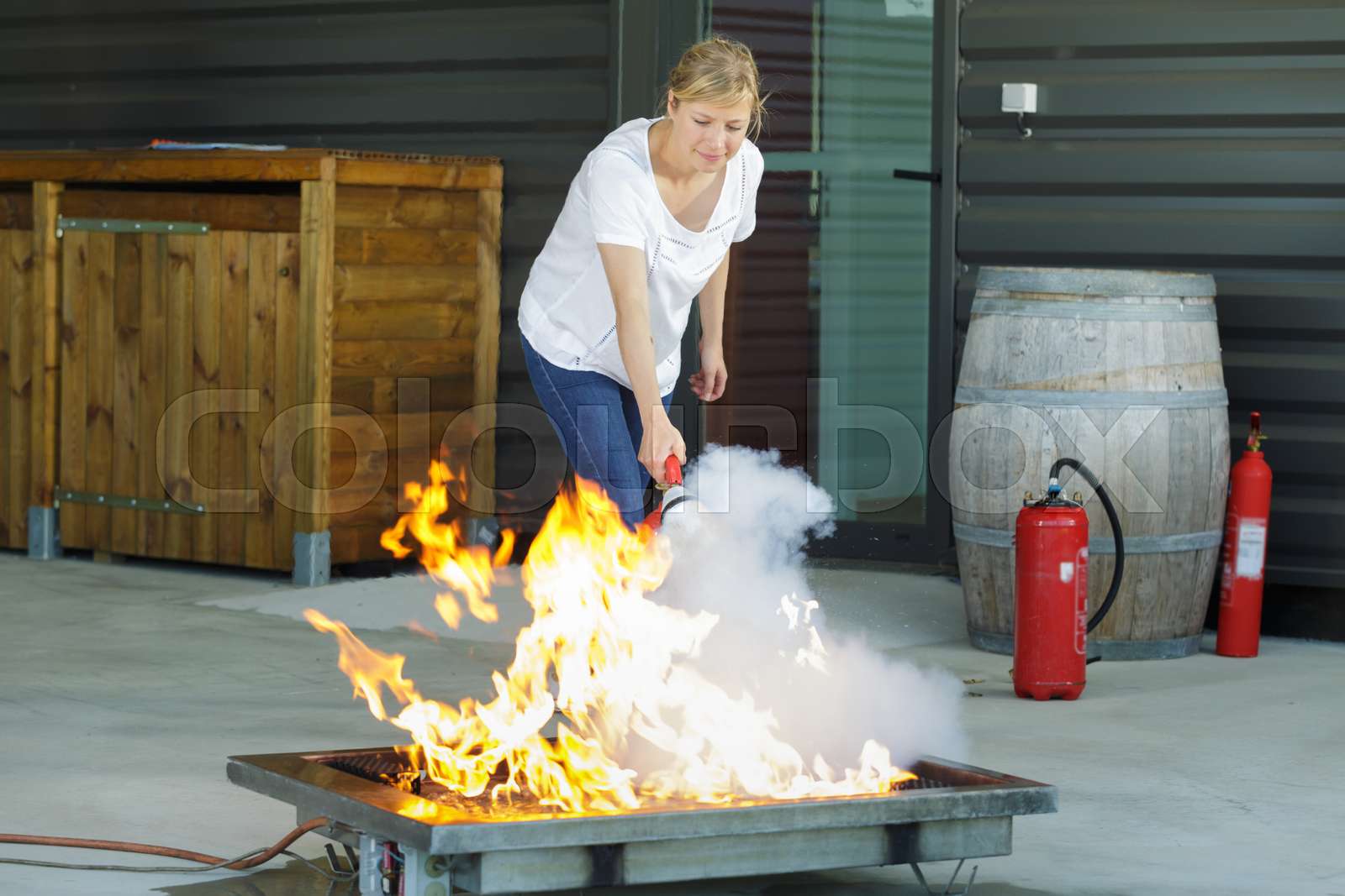 woman using fire extinguisher to stop fire coming from oven | Stock ...