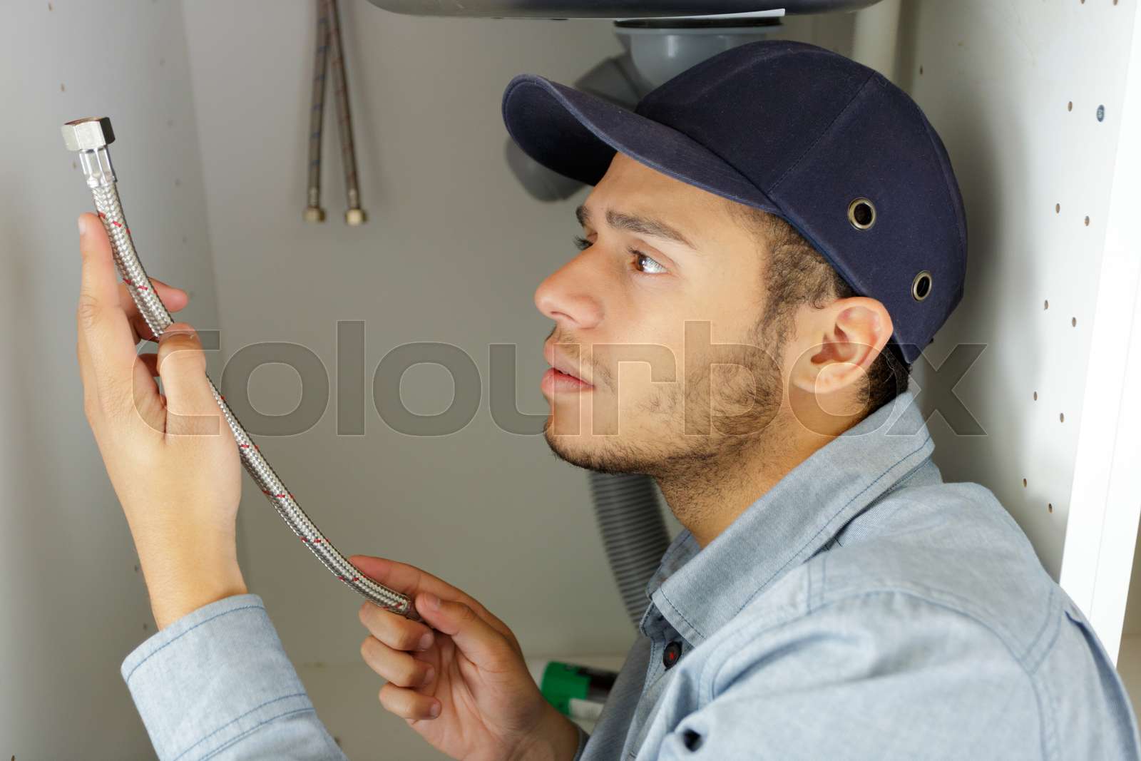 man fixing pipes under the sink | Stock image | Colourbox