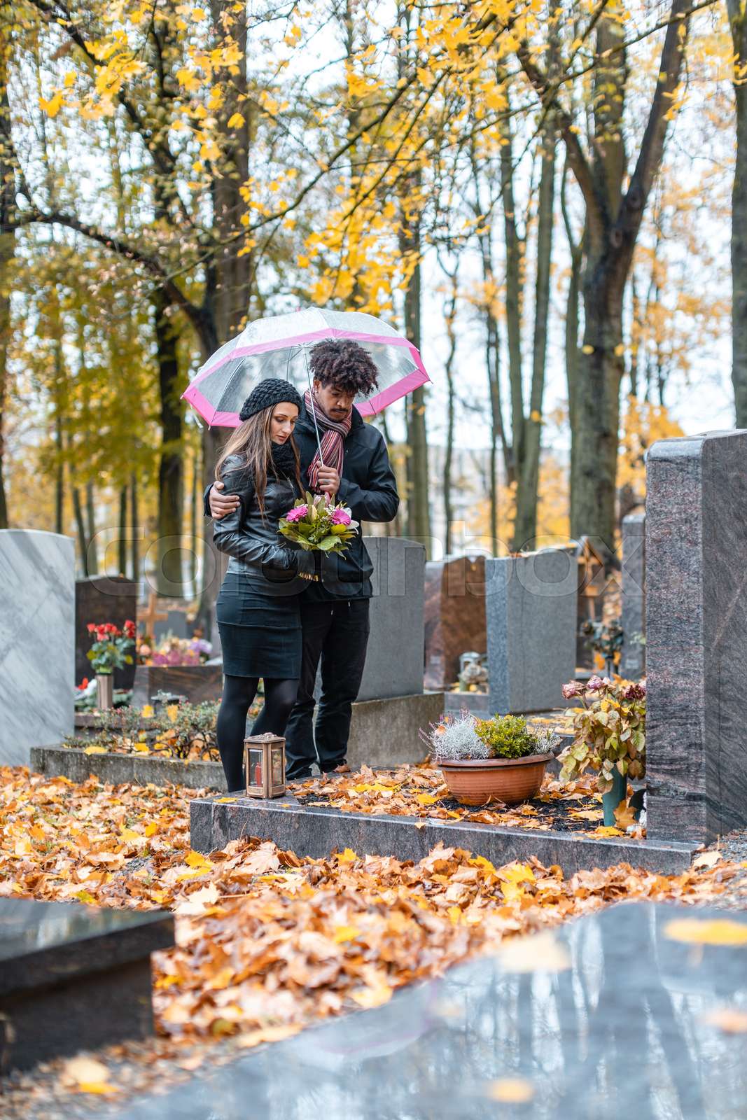 Couple mourning a deceased loved one on cemetery in fall | Stock image ...