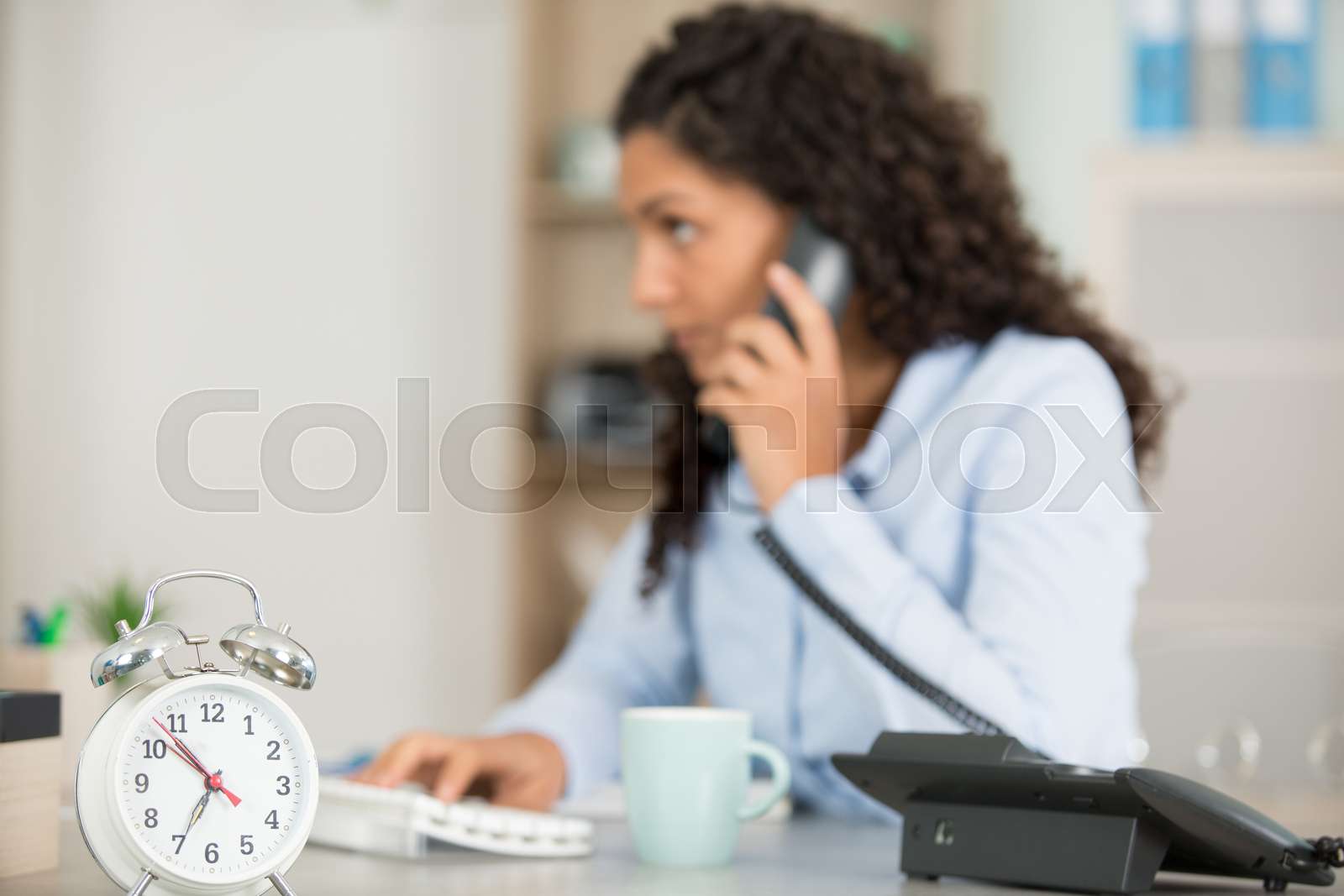 woman working in an office holding a clock | Stock image | Colourbox