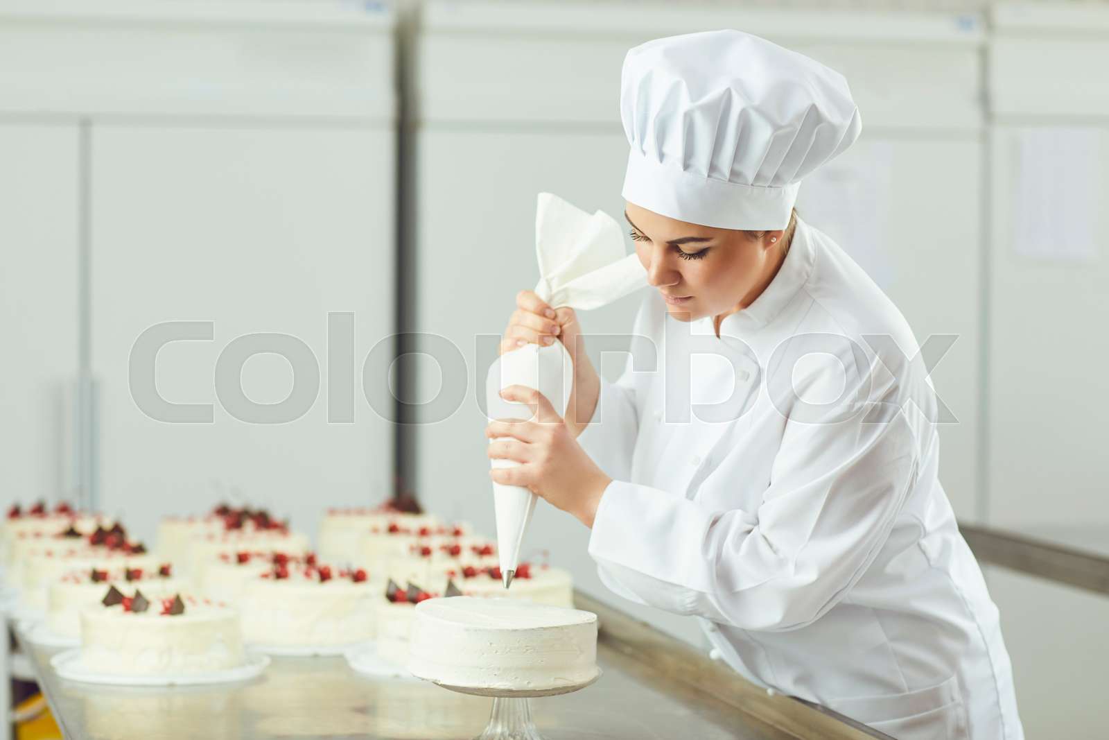 Confectioner decorating cake in pastry shop. | Stock image | Colourbox