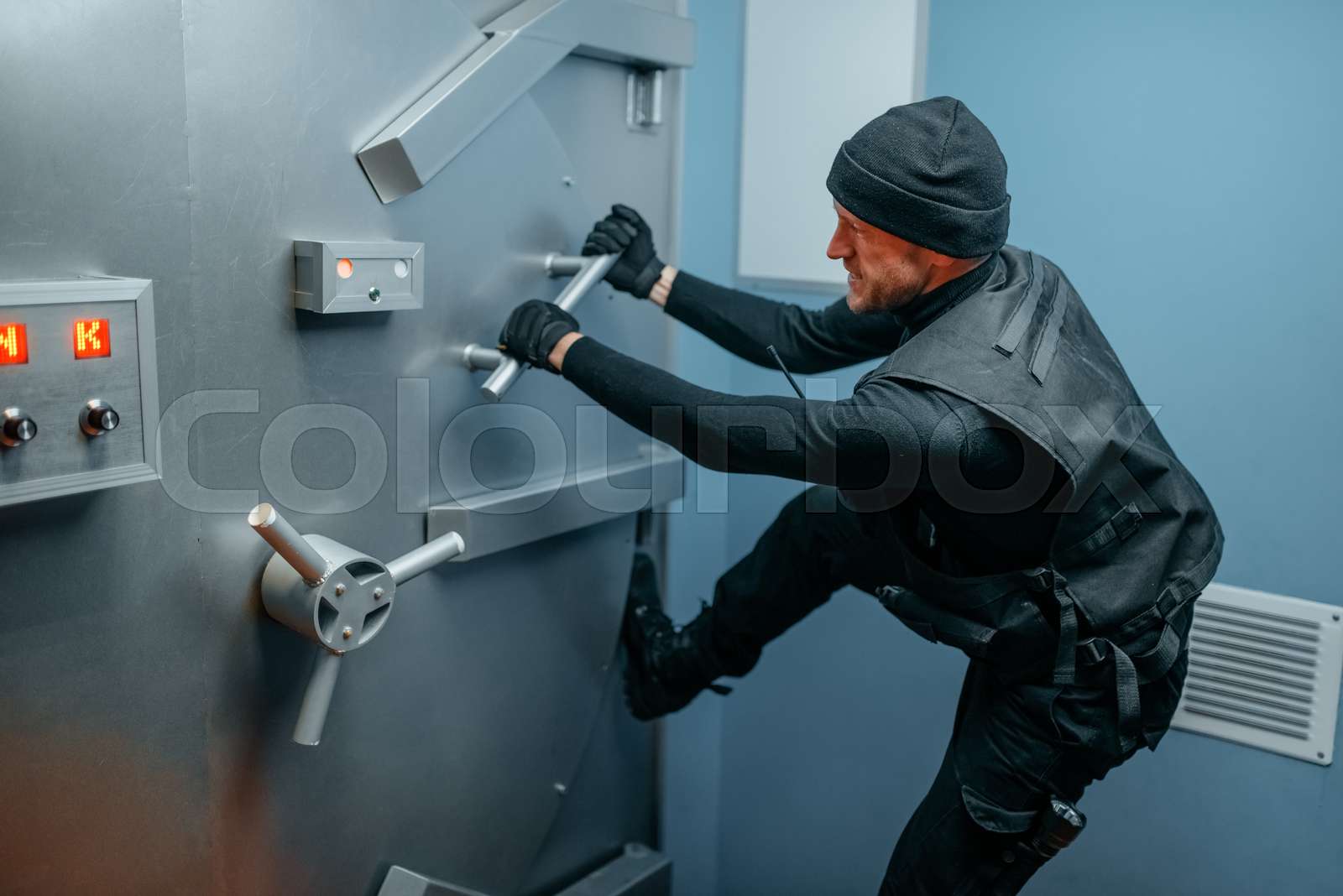 Robber in black uniform trying to break vault lock | Stock image ...