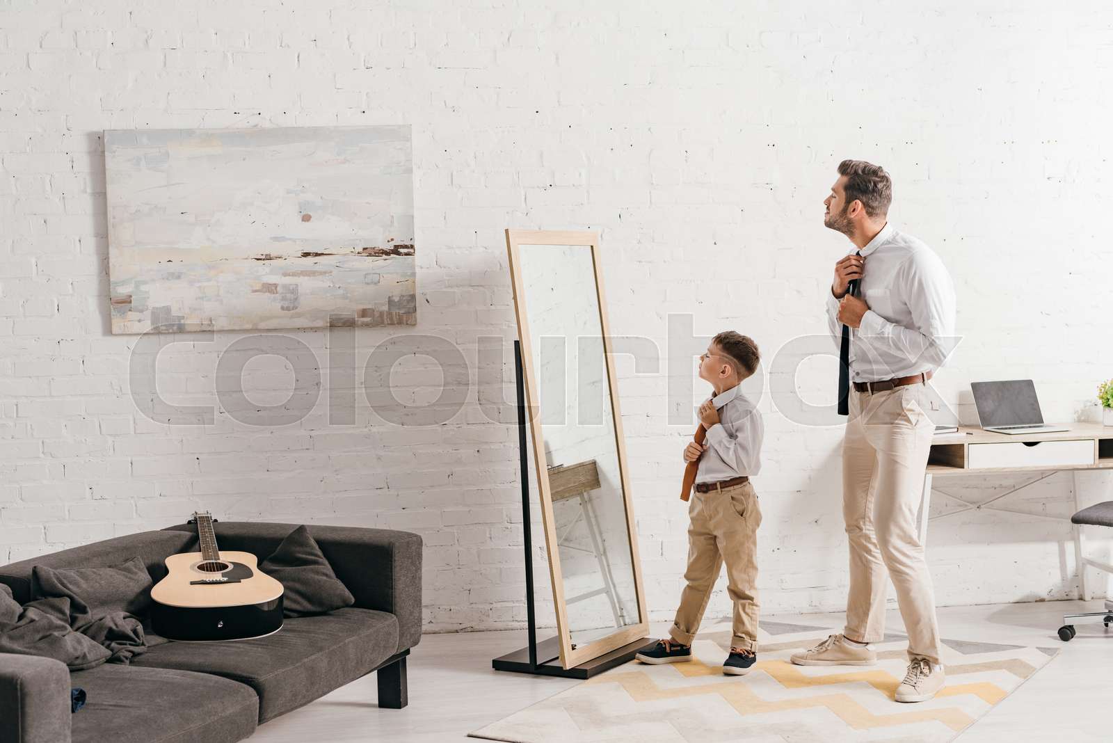 full length view of son and father in formal wear standing near mirror ...