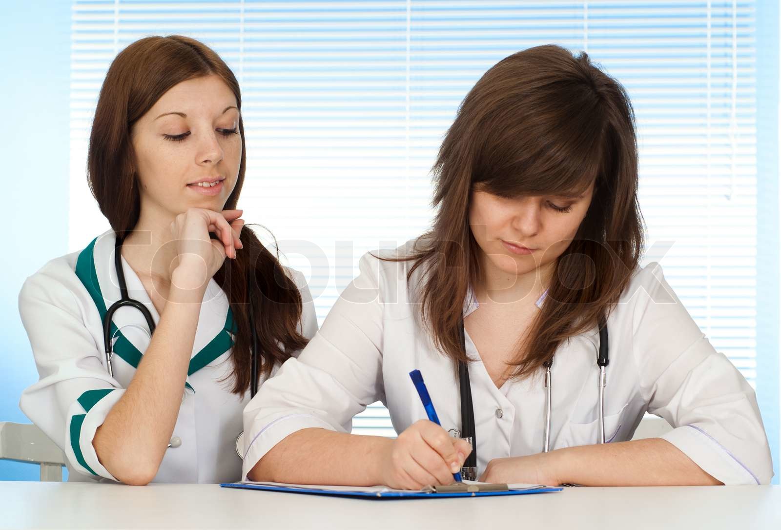 Two charming nurse sitting at the table working | Stock image | Colourbox