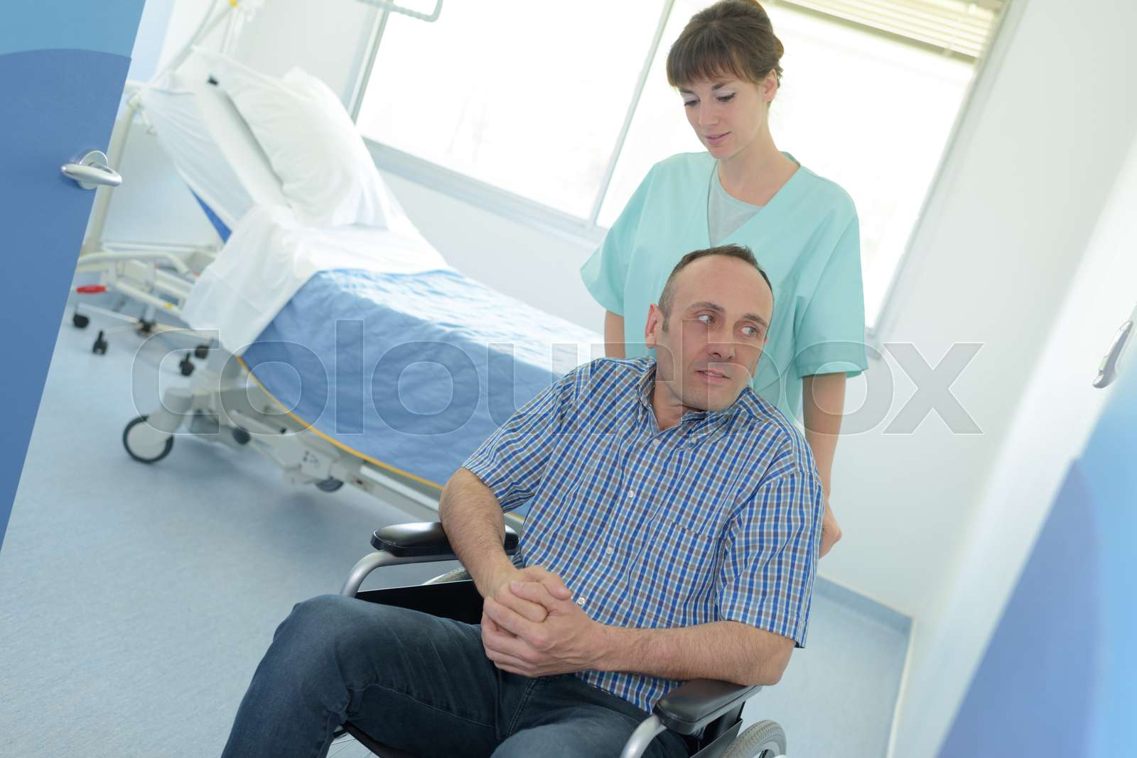 nurse pushing patient in wheelchair in hospital | Stock image | Colourbox