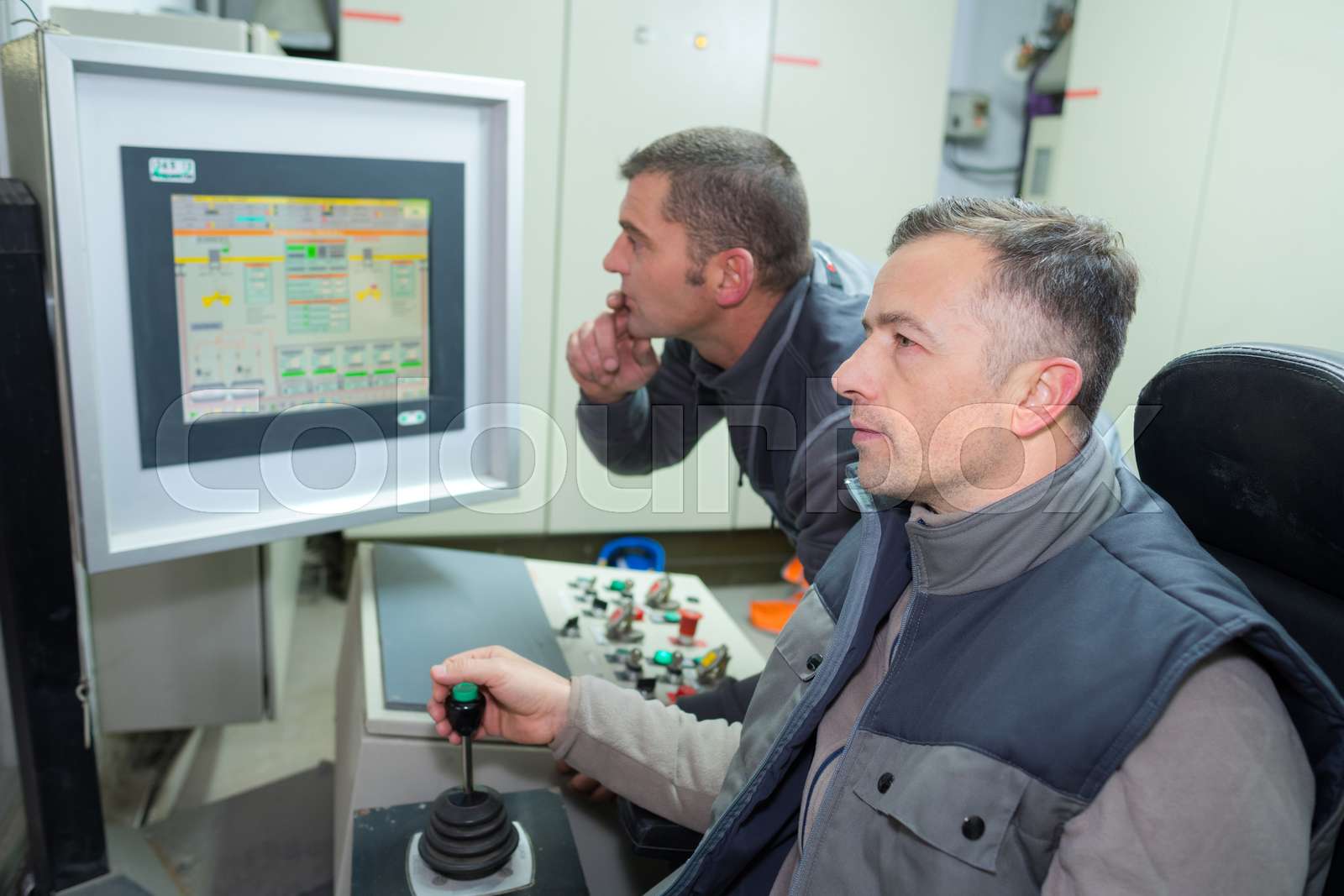 worker consulting monitor while colleague operates controls | Stock ...