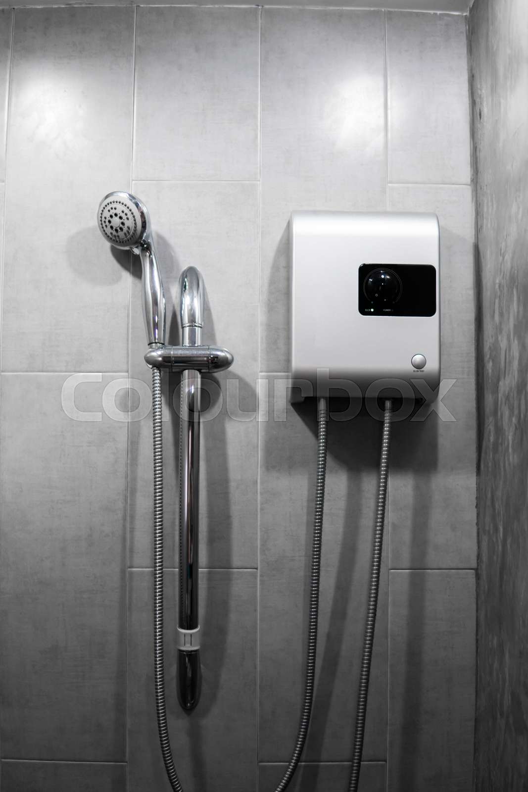 Instant tankless electric water heater installed on grey tile wall with ...