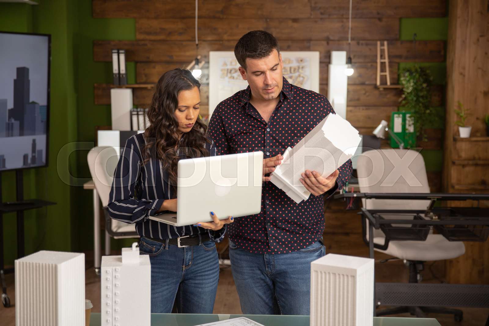 Caucasian male and female architects working on 3D printed models ...