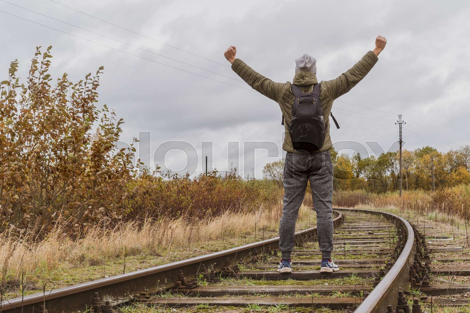 Man standing on the railway and raising hands up | Stock image | Colourbox