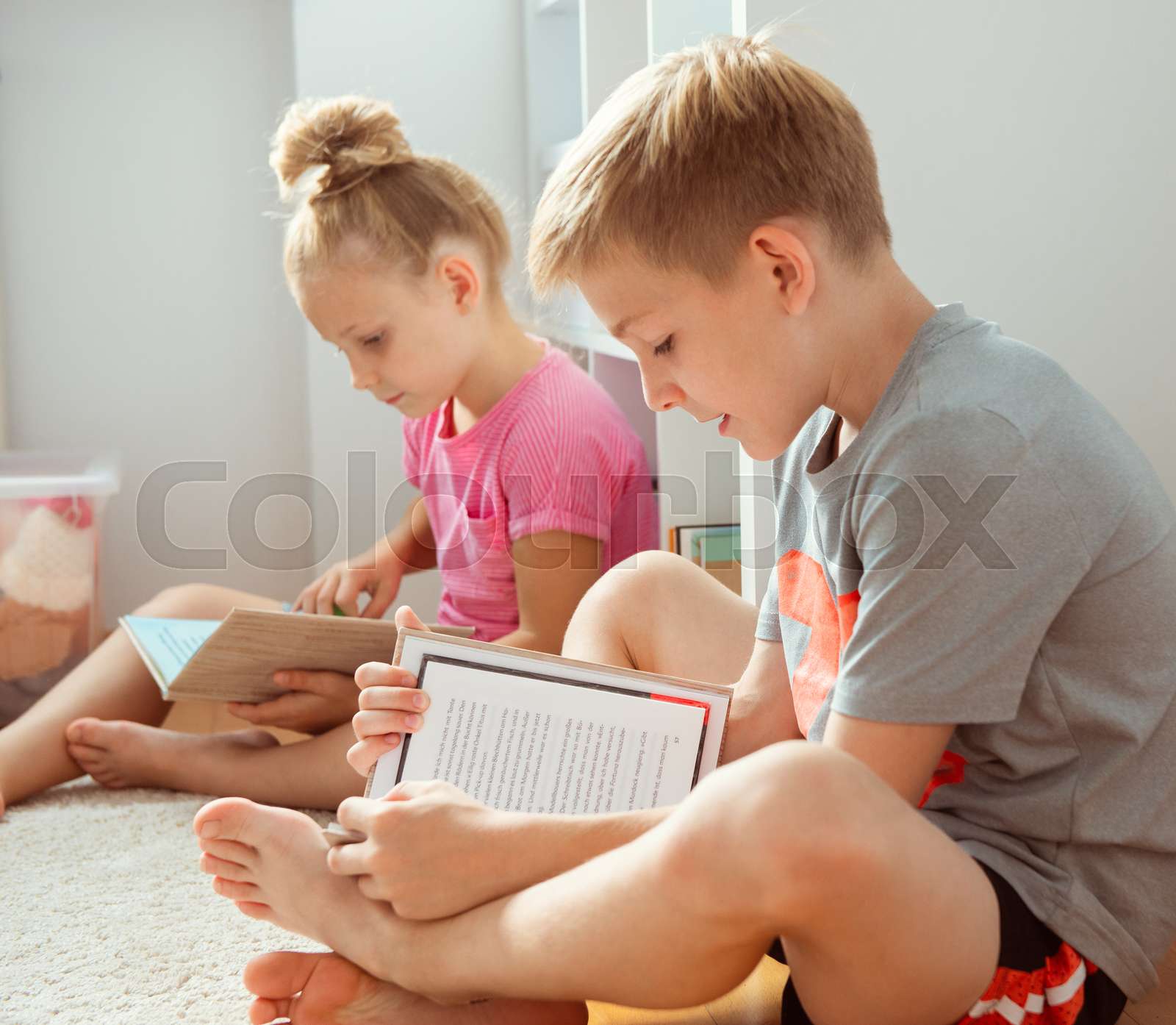Happy children reading books on the floor at the school library | Stock ...