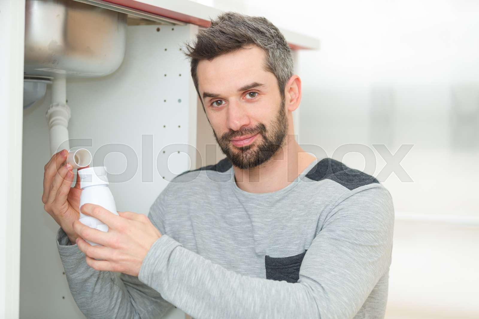 handsome plumber repairing sink pipes in bathroom | Stock image | Colourbox