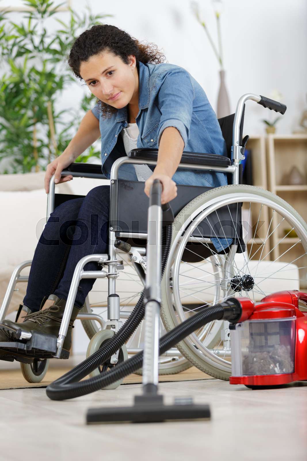 woman on wheelchair with vacuum cleaner | Stock image | Colourbox