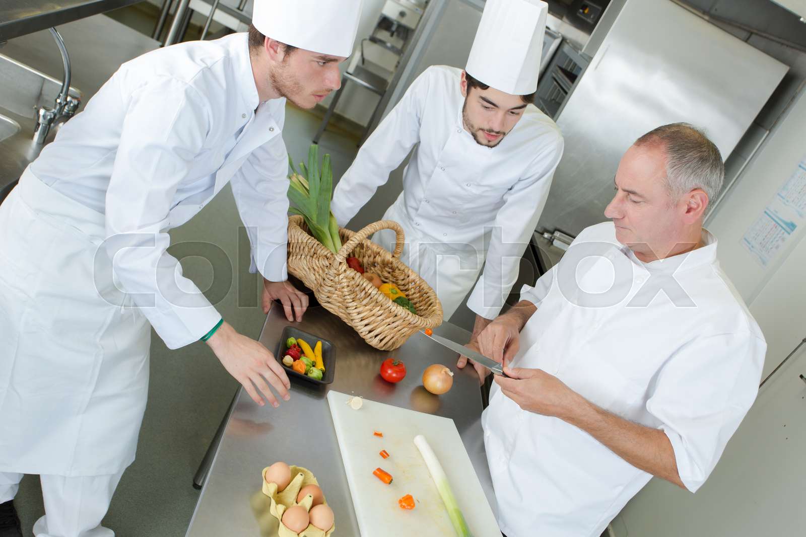 teacher helping students training to work in catering | Stock image ...