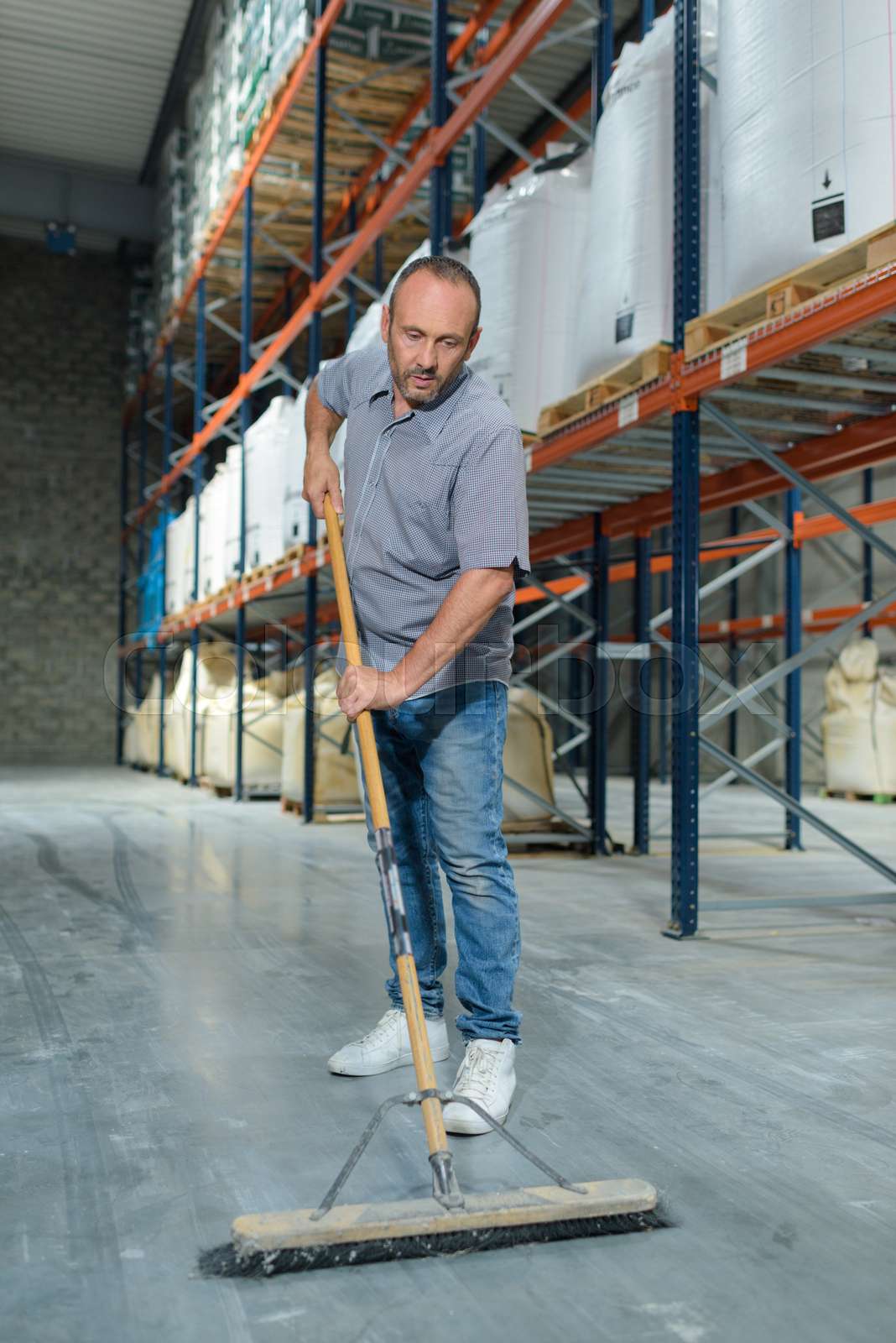 mature man sweeping warehouse floor | Stock image | Colourbox