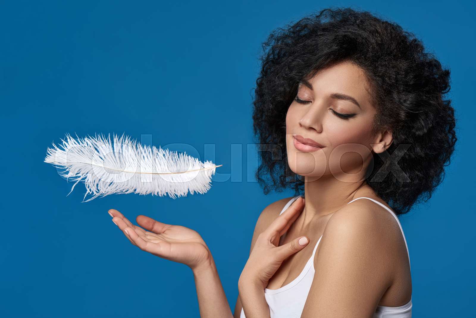 Beautiful mixed race woman catching white ostrich feather falling on ...